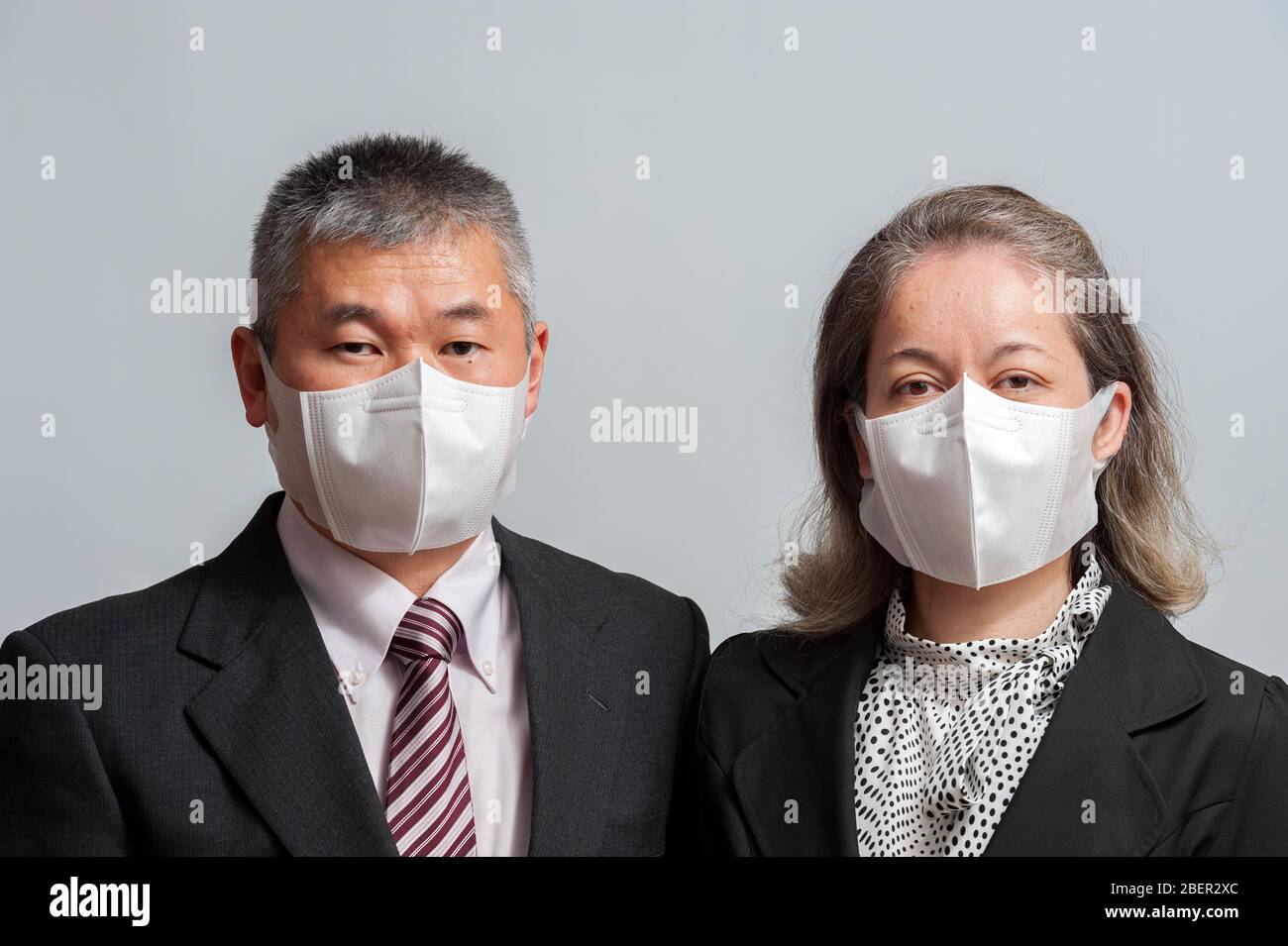 Front view of middle aged Asian couple in formal wear wearing white ...
