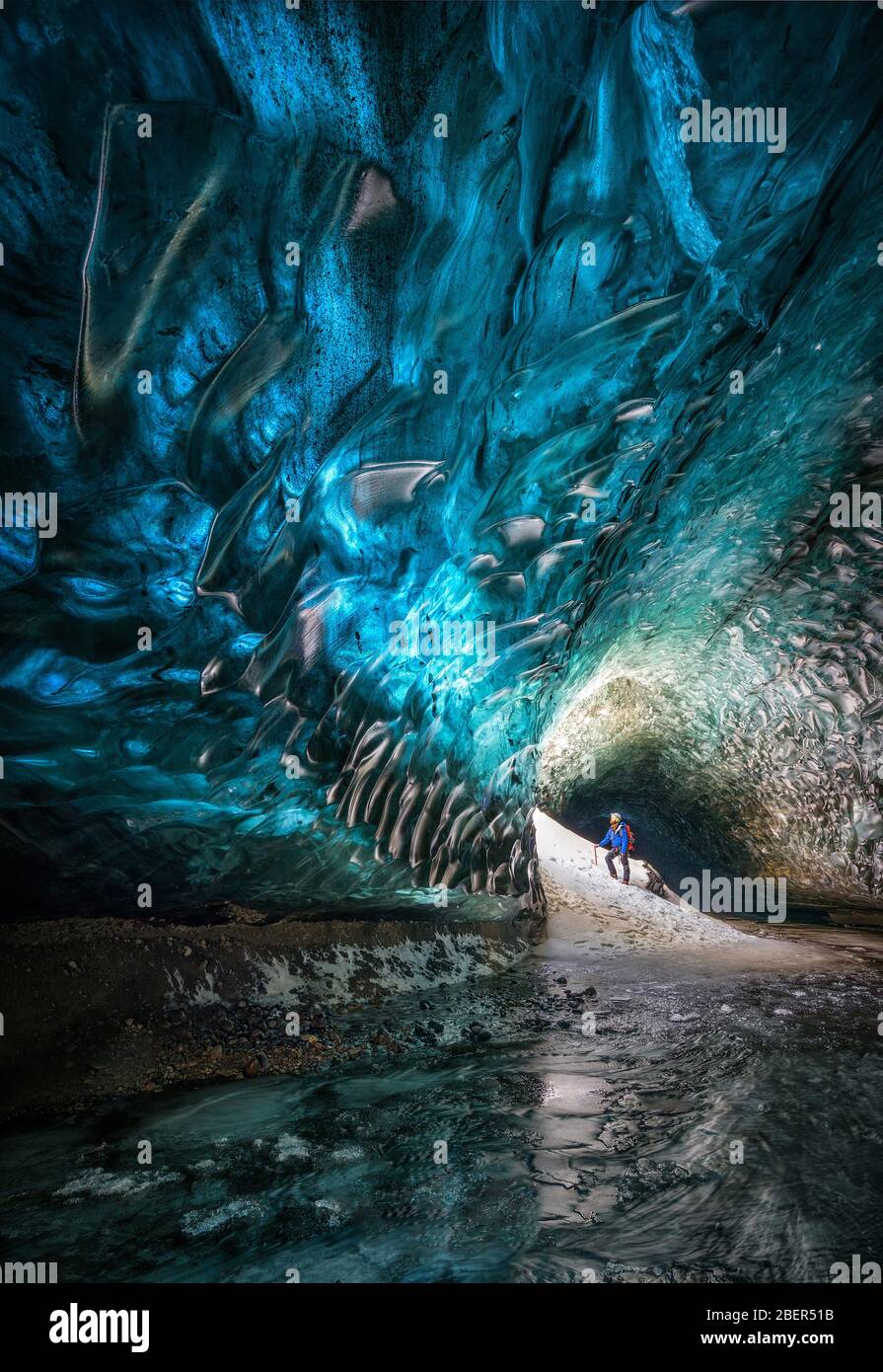 Ice cave showing a guy looking at the ice running through the holes ...