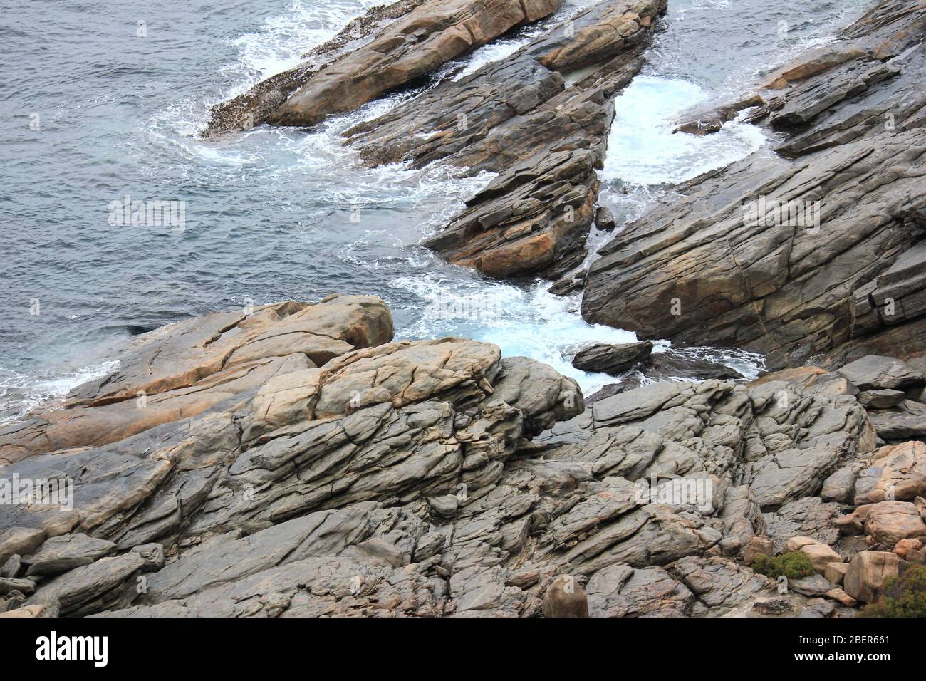 Rugged rocks layering out of the sea Stock Photo - Alamy