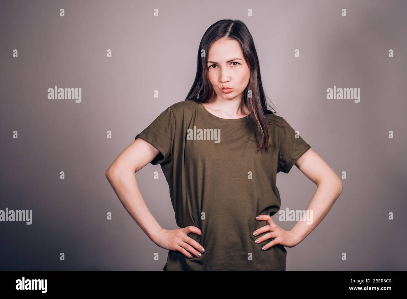 Beautiful young girl making a face, makes a grimace to the lips and ...