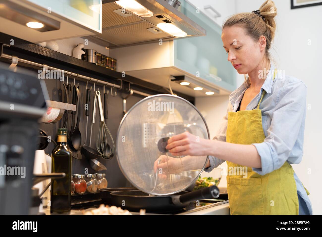 Stay at home housewife woman cooking in kitchen, stir frying dish in a ...