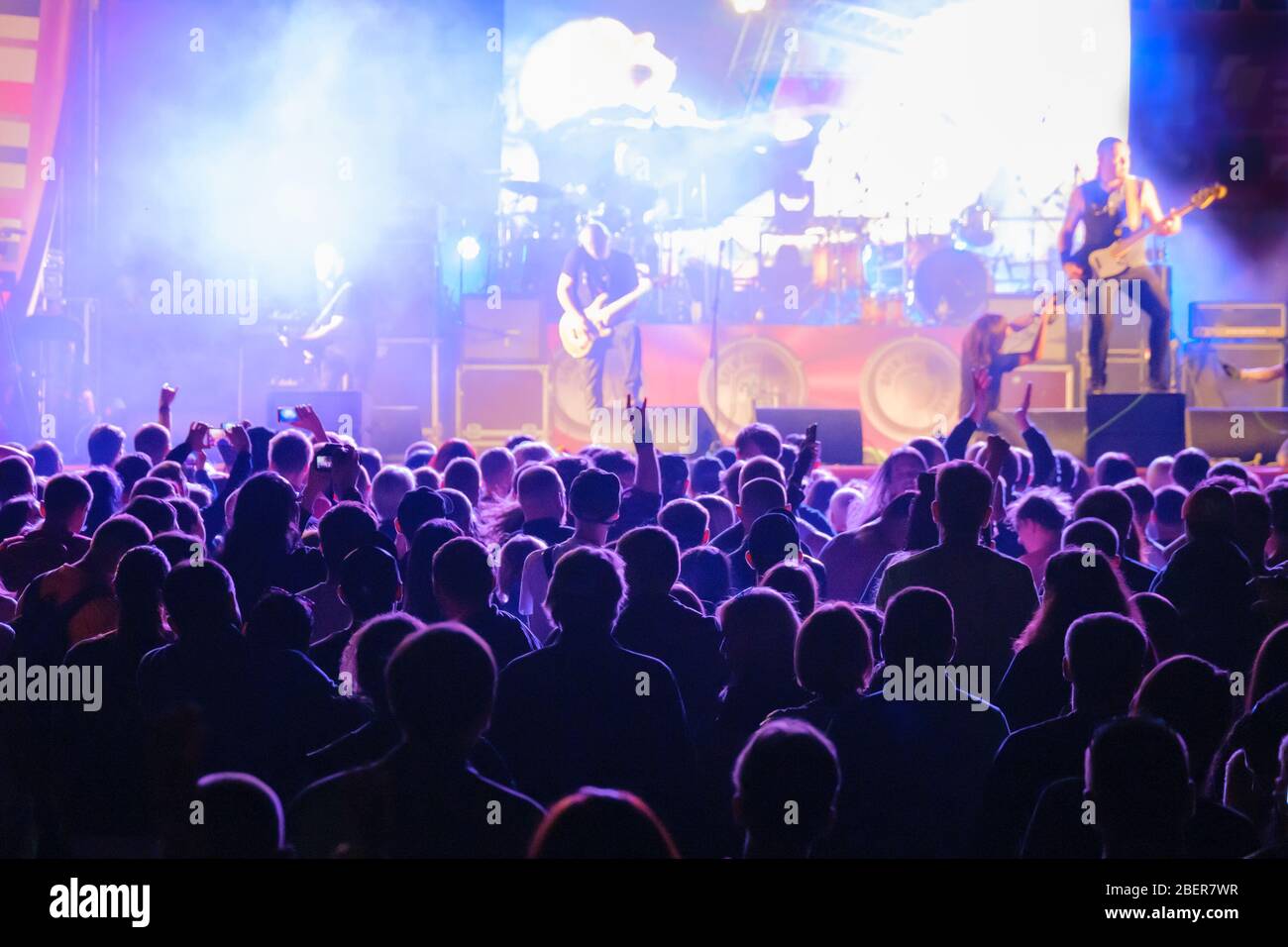 Fans in dark neon listening to rock band on stage Stock Photo - Alamy