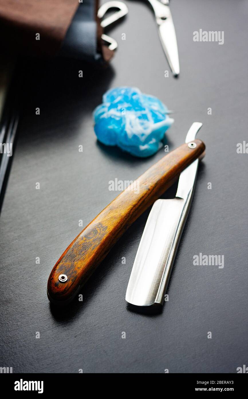 Straight razor, shaving foam, leather tool and scissors on black wooden ...