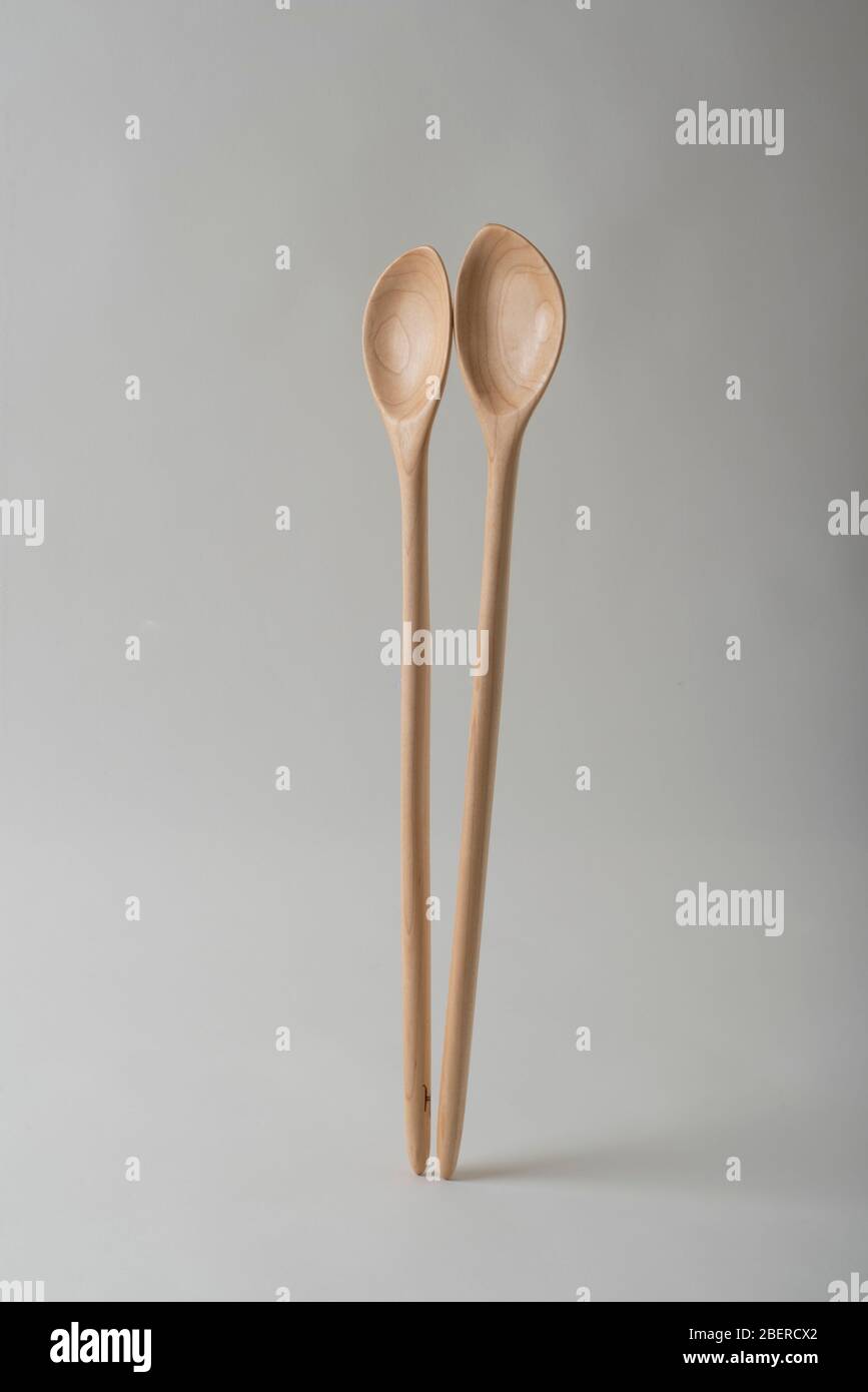 Two, long, handmade spoons of Canadian maple wood set against a white ...