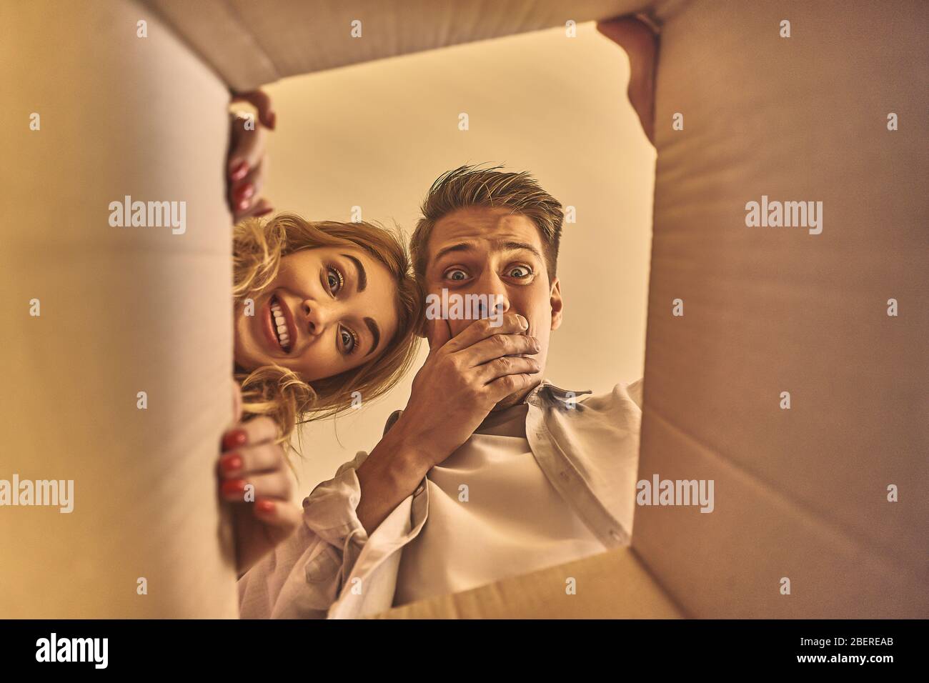 Happy couple with surprised faces checking the box after moving into ...