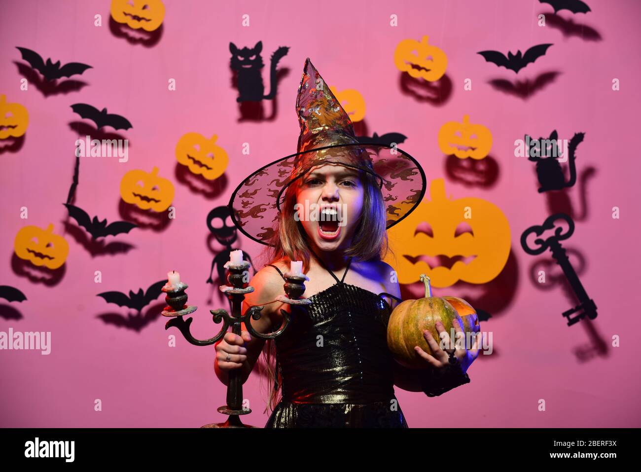 Kid in spooky witches costume holds carved pumpkin and chandelier ...