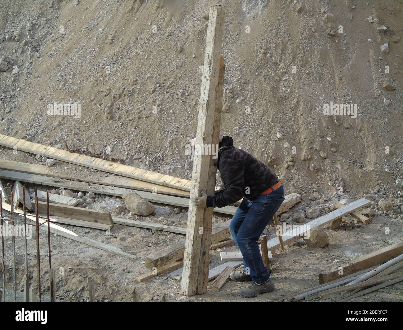 Worker handling wooden axis in a construction site Stock Photo - Alamy