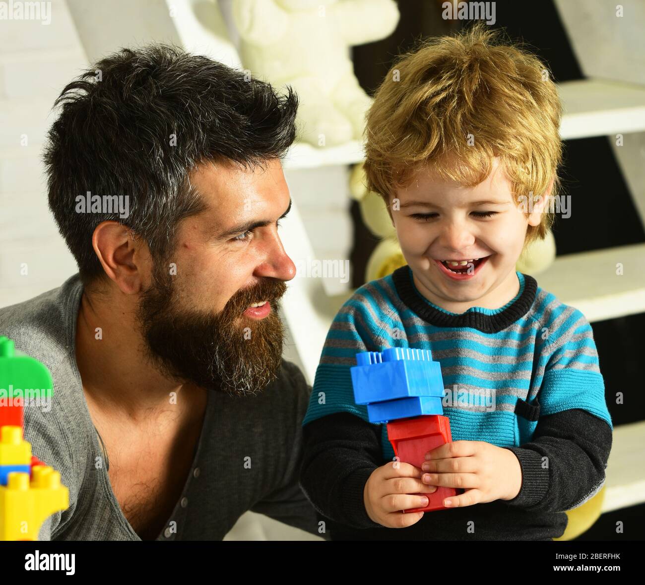 Father and son with happy faces create colorful constructions with toy ...