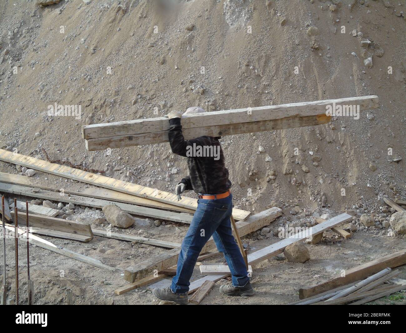 Worker handling wooden axis in a construction site Stock Photo - Alamy