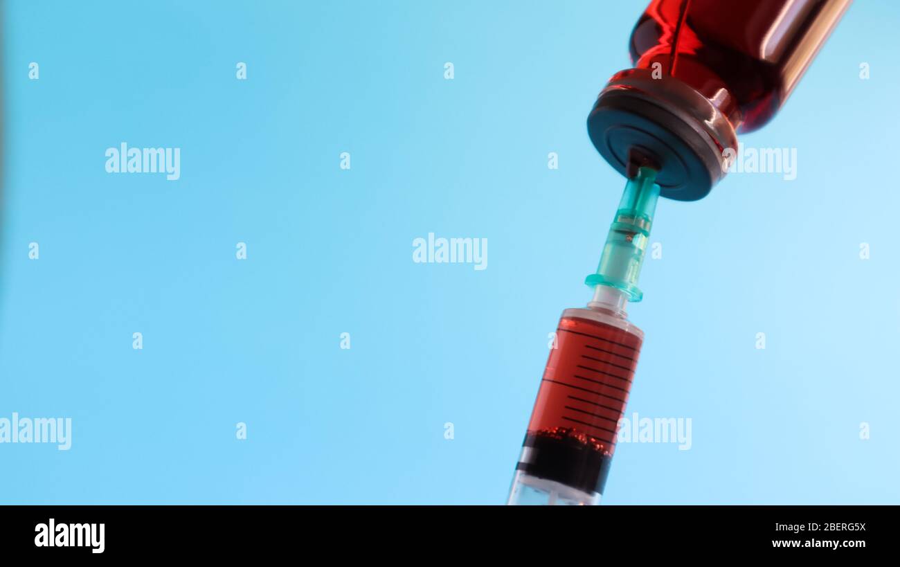 Coronavirus flu and pandemic vaccines, syringe and vial with red liquid ...