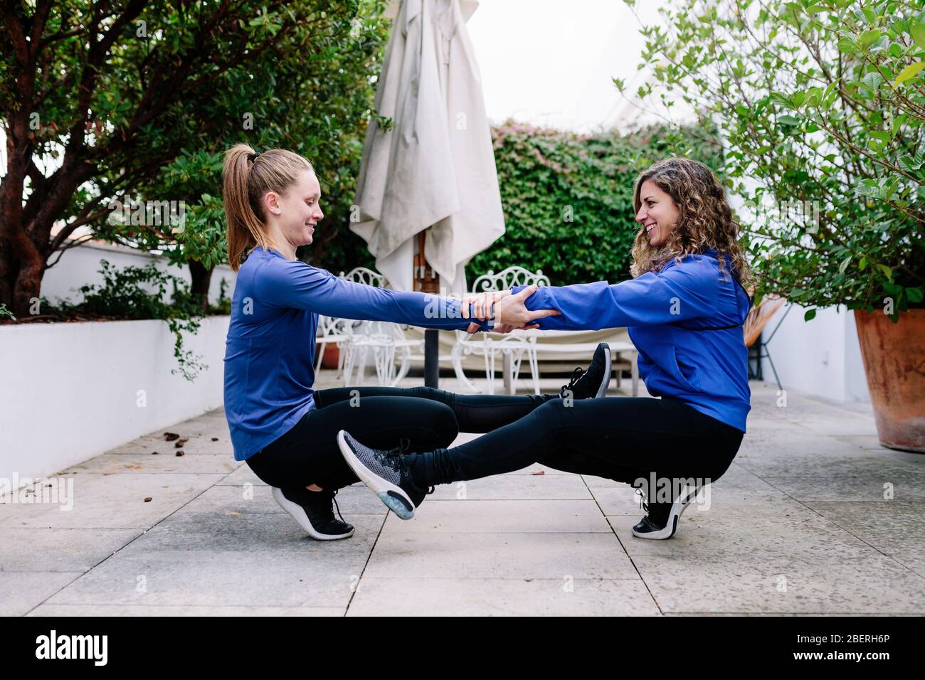 Two young women doing exercise together on a terrace Stock Photo - Alamy