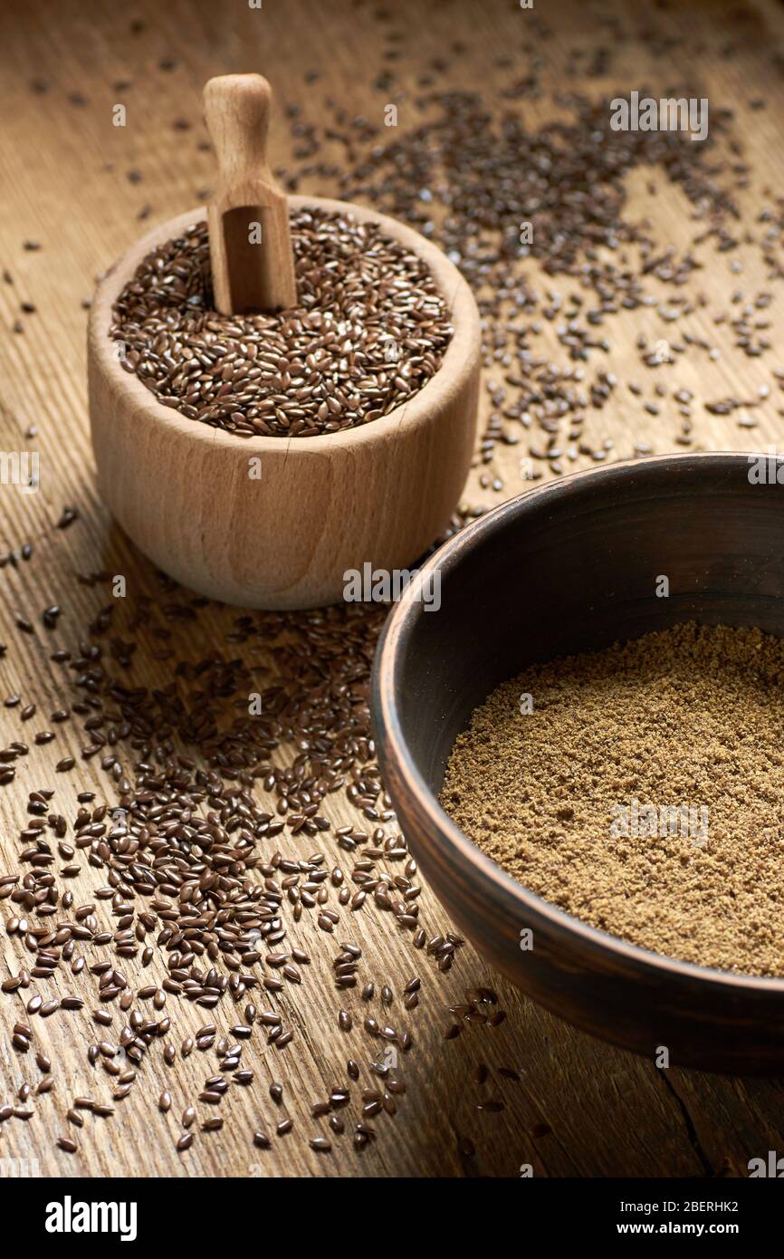 Flax seed coarse ground flour in a clay bowl with linseed wooden bowl ...