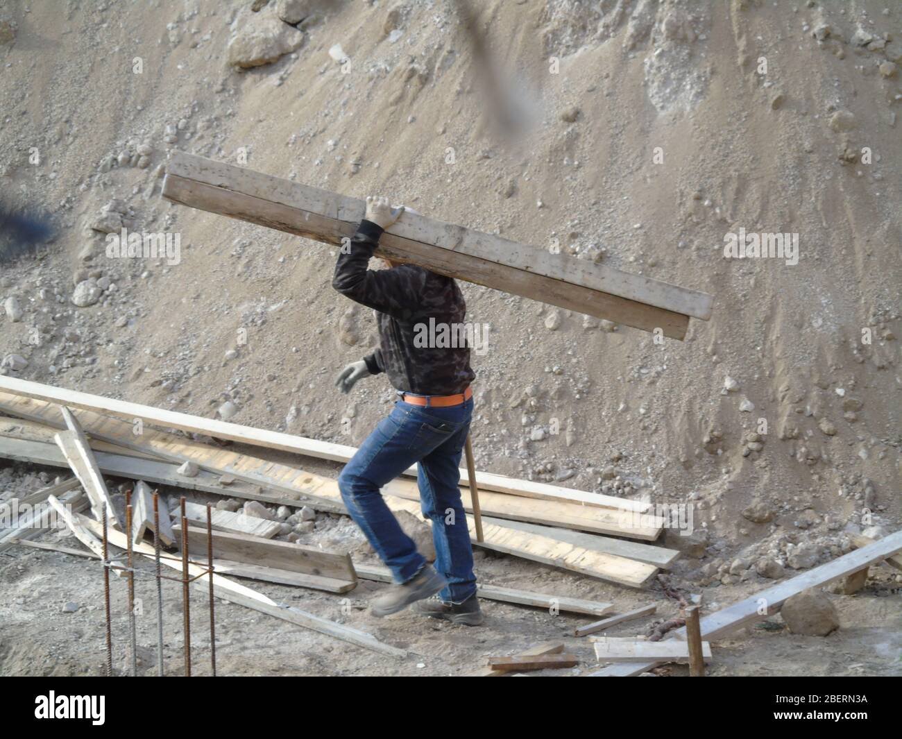 Worker handling wooden axis in a construction site Stock Photo - Alamy