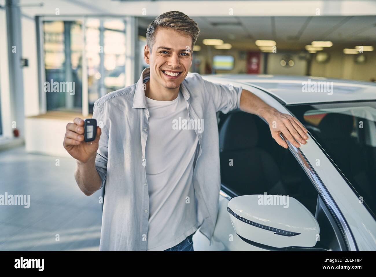 Happy man buying a new car in showroom Stock Photo - Alamy