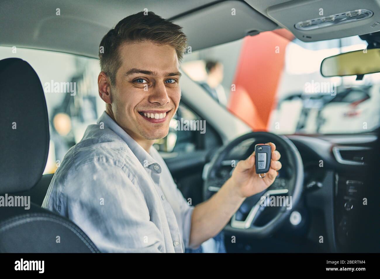 Happy man with key sitting in automobile Stock Photo - Alamy
