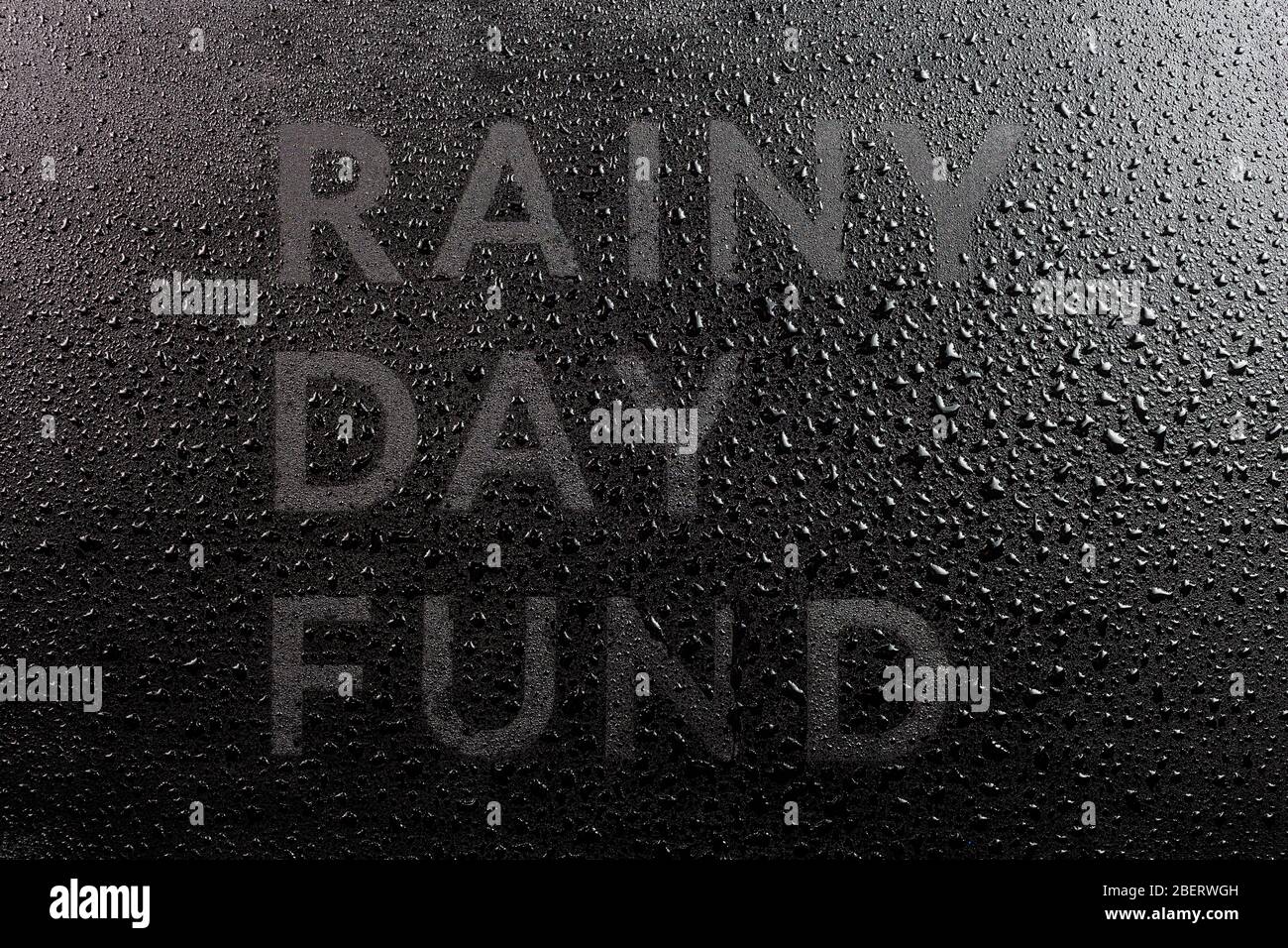 the dry words rainy day fund covered from water drops on black surface ...