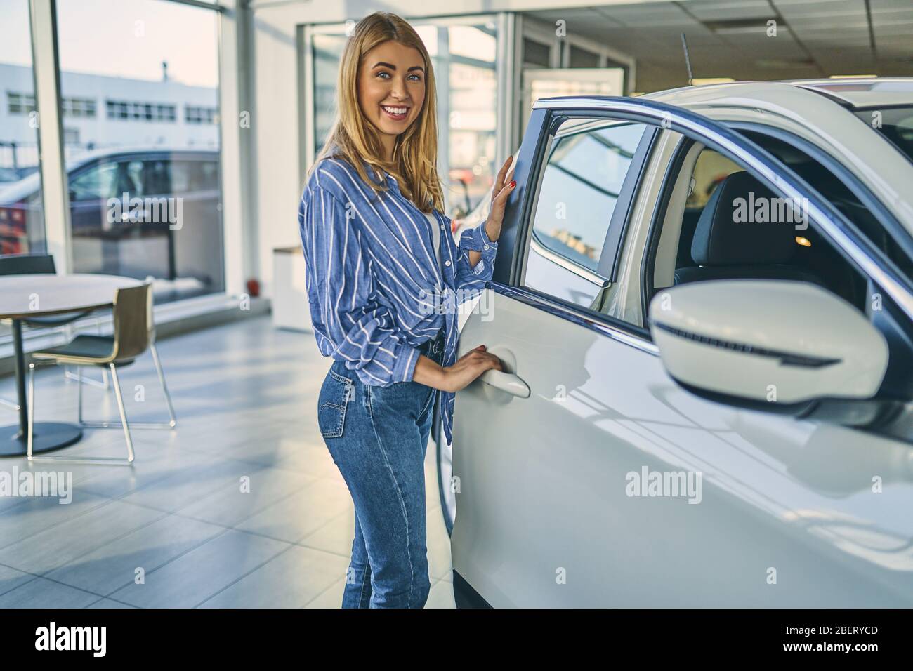 Happy girl opening the car door in car showroom Stock Photo - Alamy