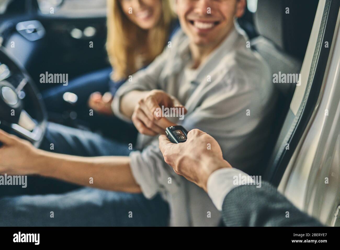 Dealer hand giving a key to new car owners Stock Photo - Alamy