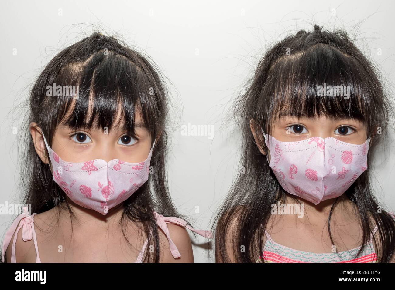 Asian female twins wearing a mask to protect against the Corona virus ...