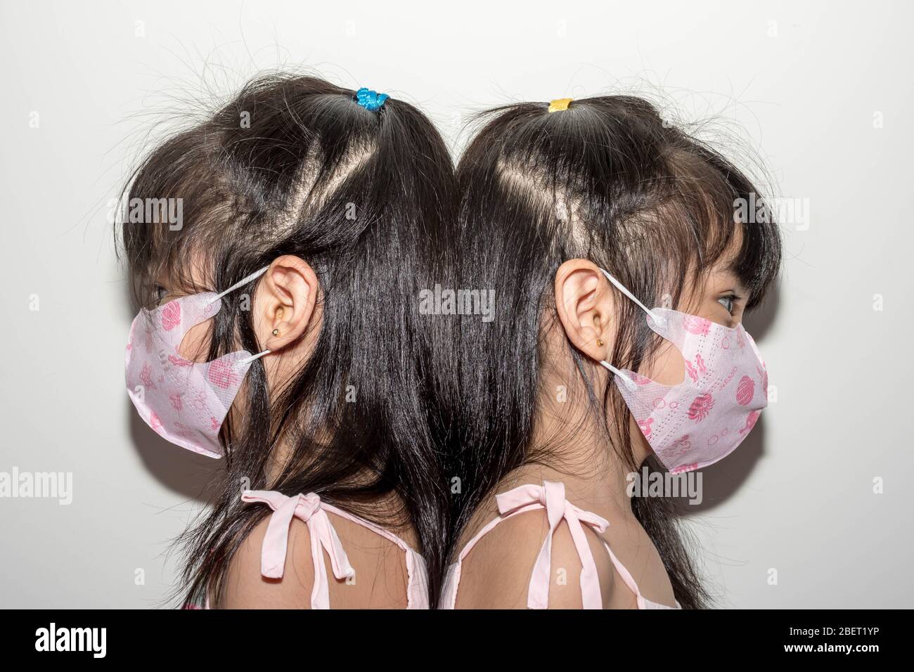 Asian female twins wearing a mask to protect against the Corona virus ...