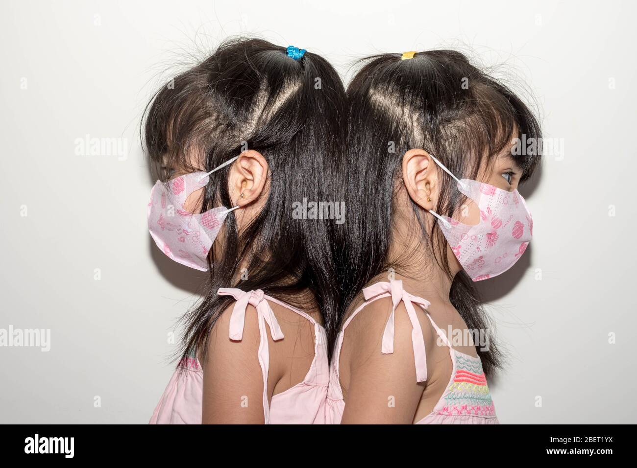 Asian female twins wearing a mask to protect against the Corona virus ...