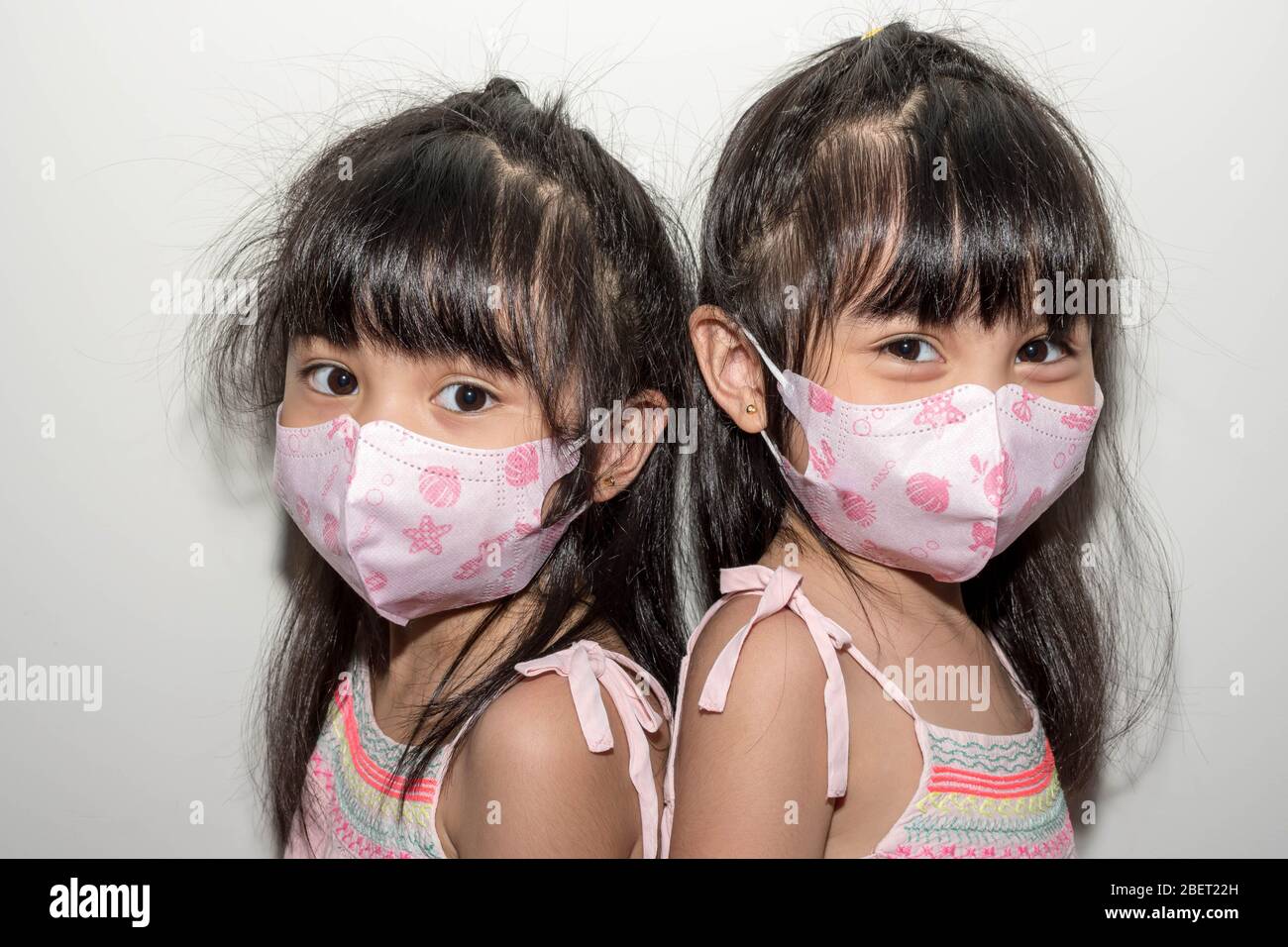 Asian female twins wearing a mask to protect against the Corona virus ...