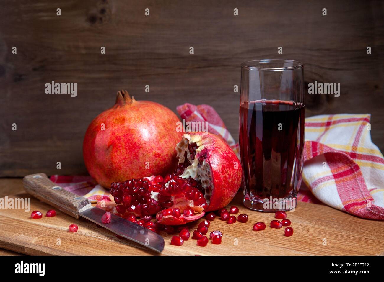 Composition of ripe red pomegranate with vintage knife and glass of ...