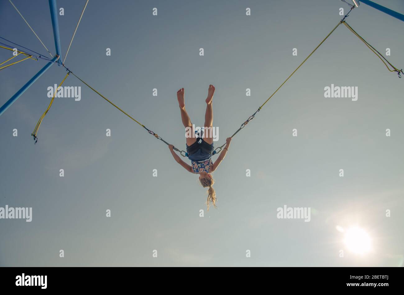 active little young teen girl jumping in trampoline high into the blue ...