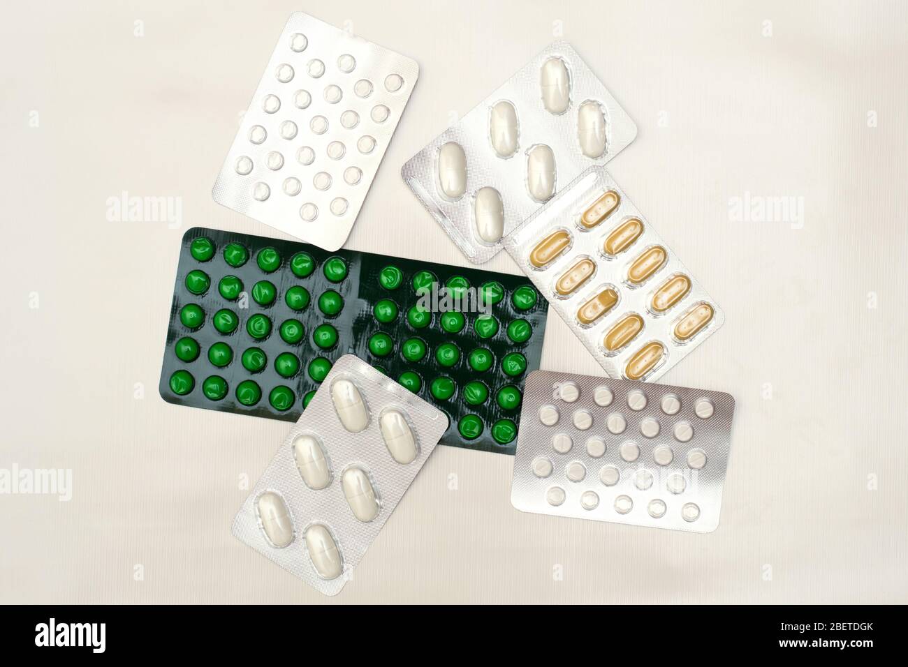 Different kinds of tablets in blasters on a light background, medical ...