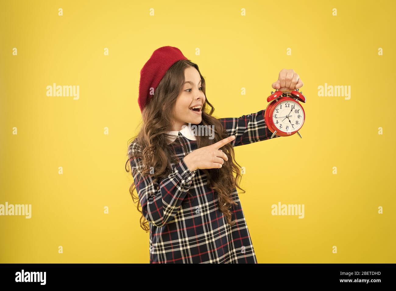 Girl with alarm clock. Set up alarm clock. Child little girl hold red ...