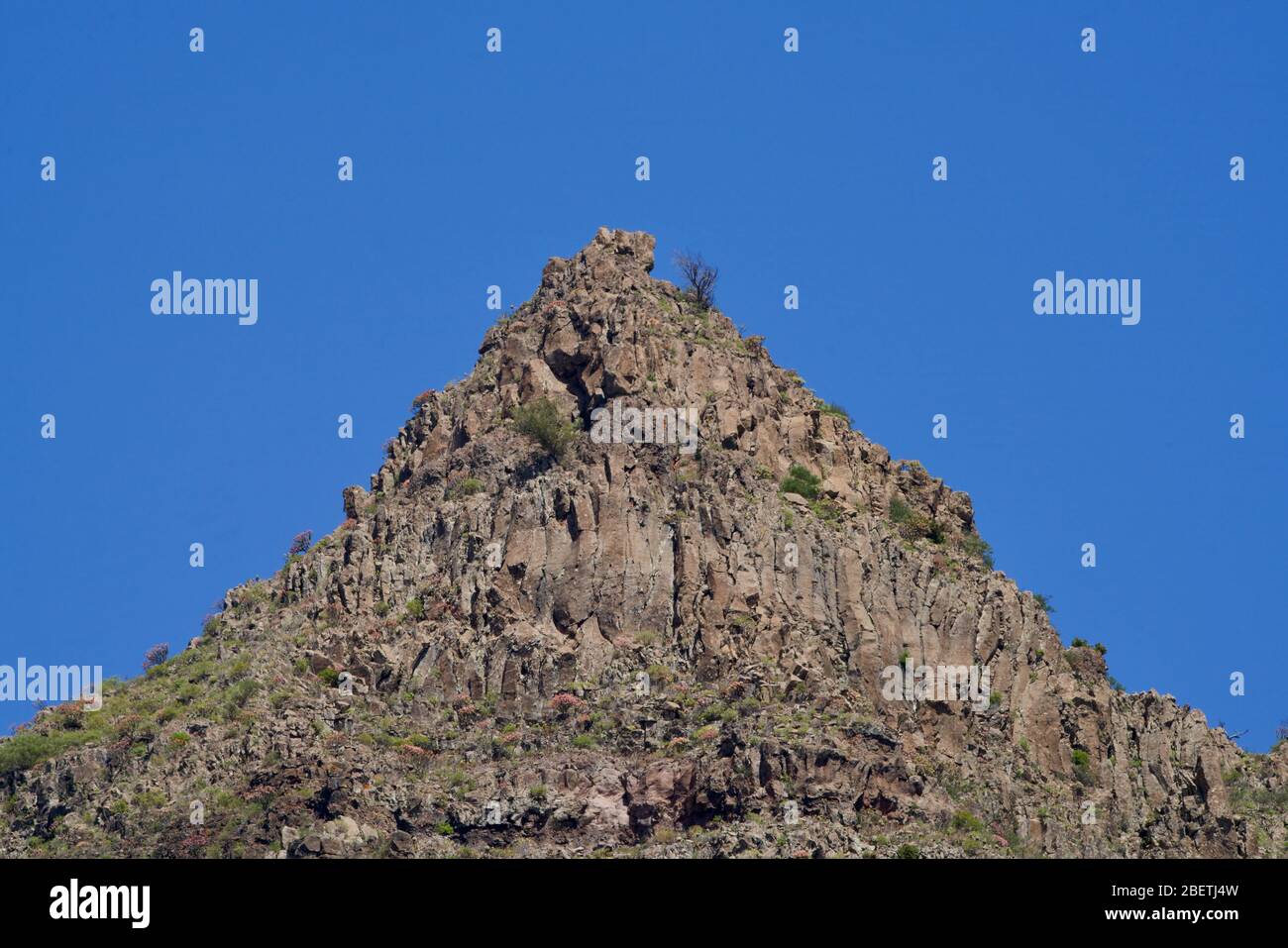 Triangular volcanic rock under a perfect blue sky Stock Photo - Alamy