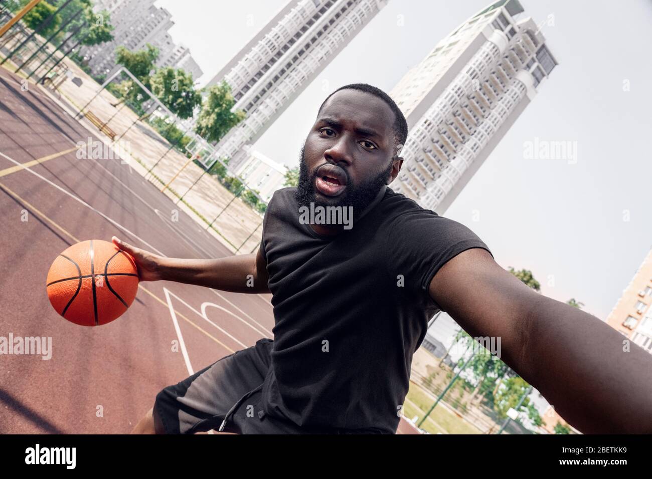 Outdoors Activity. African man playing basketball on court taking ...