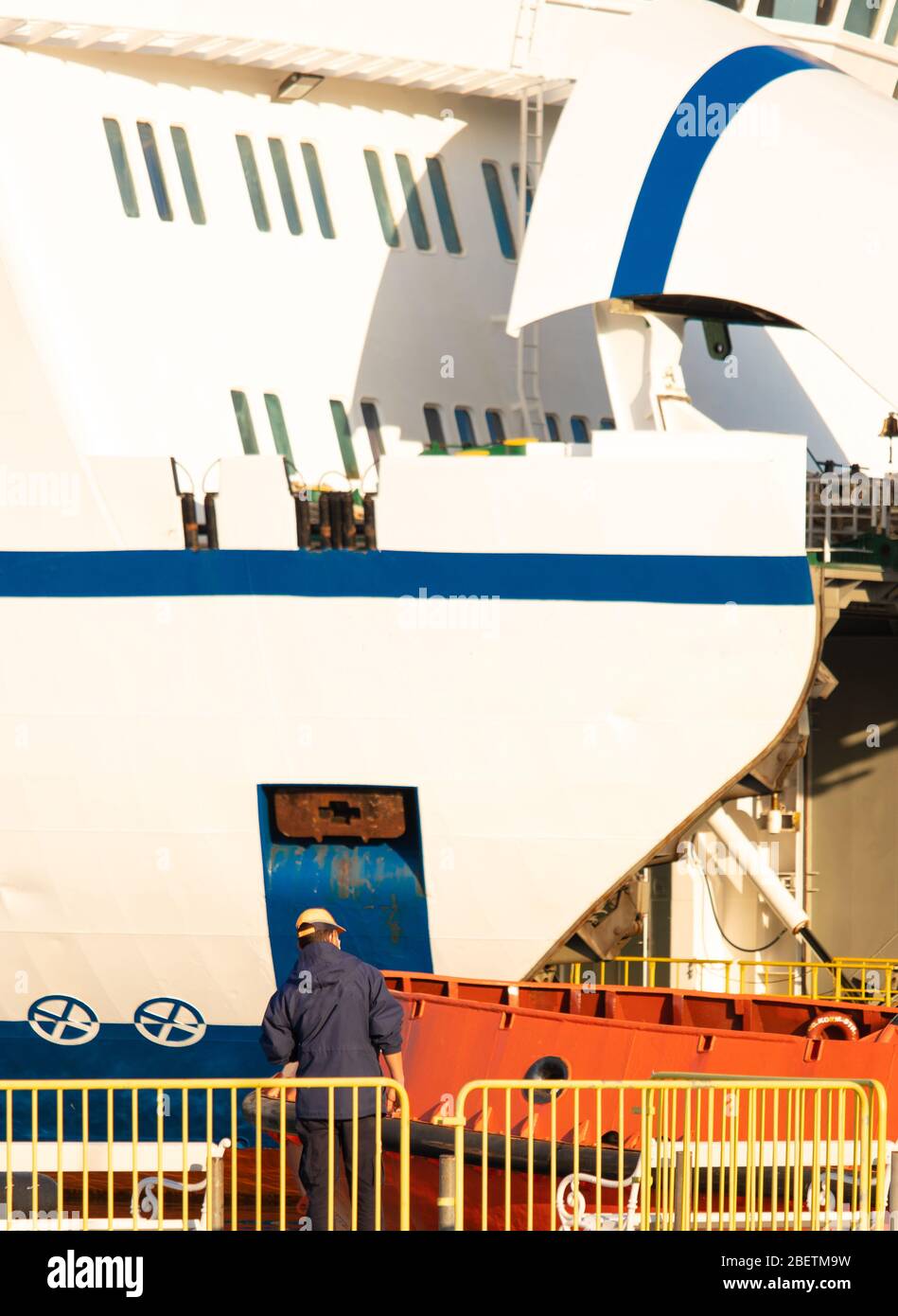 Ferry ship ocean liner worker standing behind a yellow fence, seen from ...