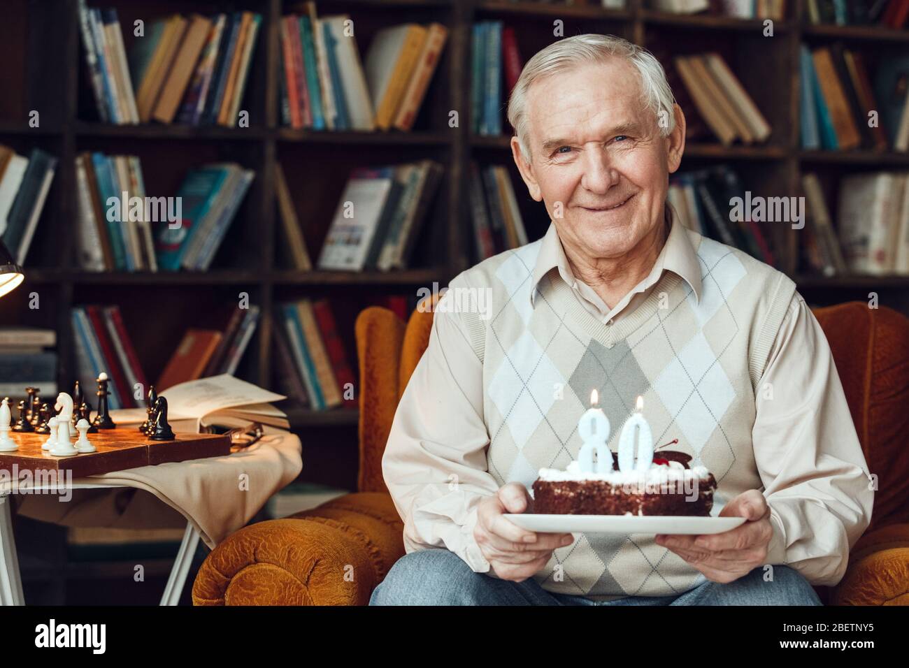 Senior man alone sitting at library holding cake smiling happy Stock ...