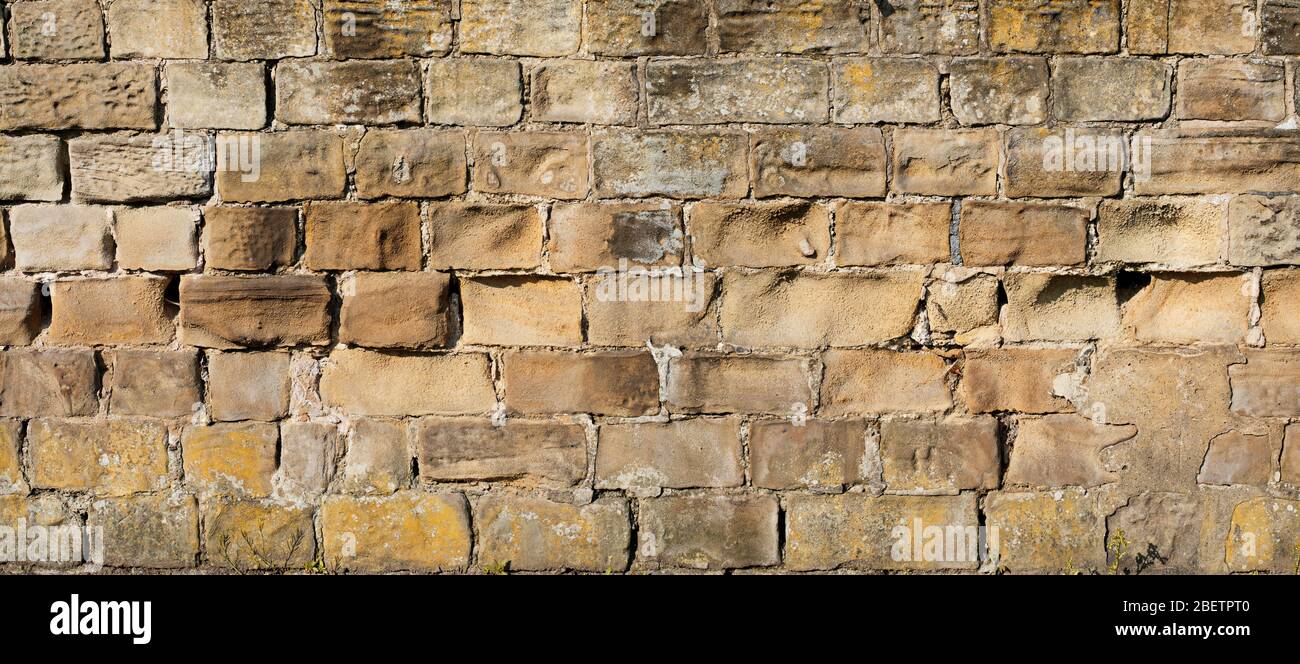 old yellow and brown sandstone wall made of blocks of irregular shape ...