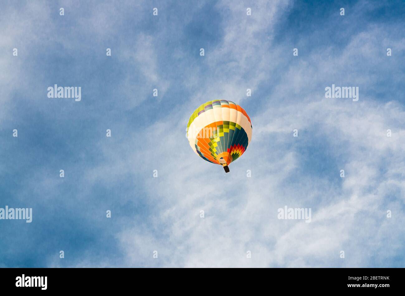 Colorful color hot air balloon in flight flying against blue sky with white clouds background ...