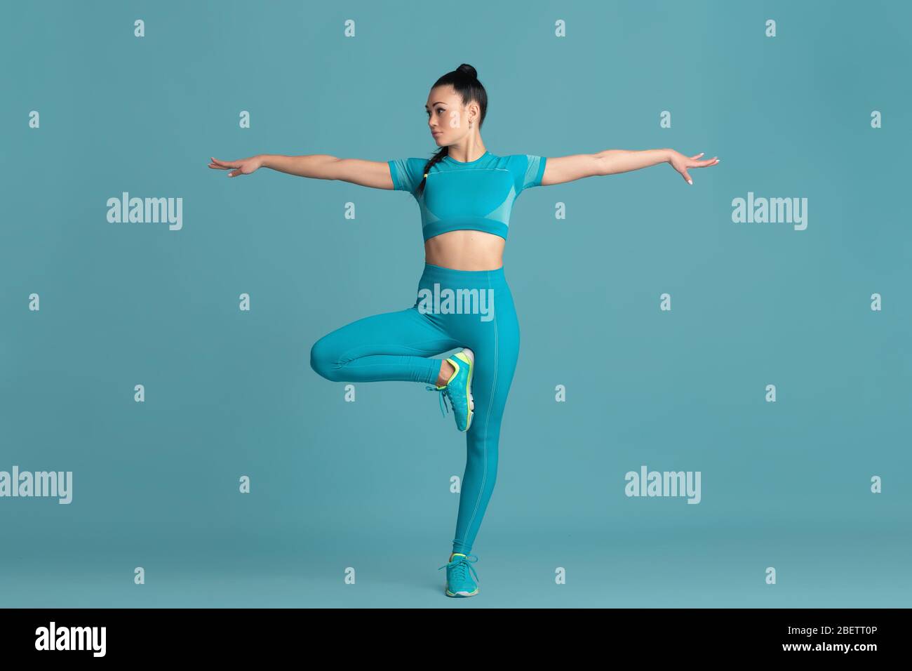 Balance. Beautiful young female athlete practicing in studio ...