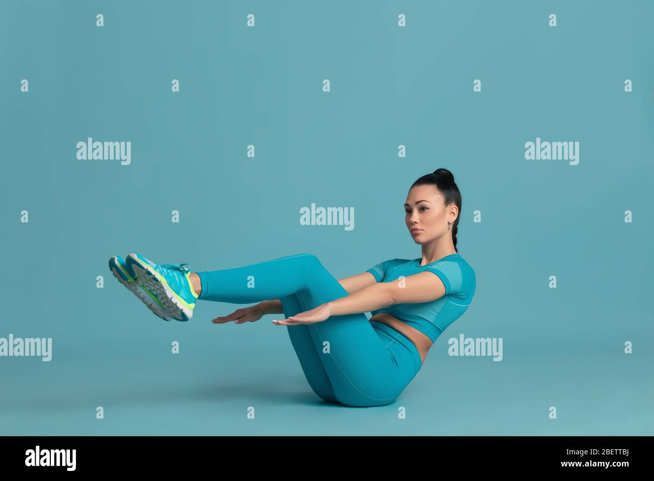 Upper body, ABS. Beautiful young female athlete practicing in studio ...