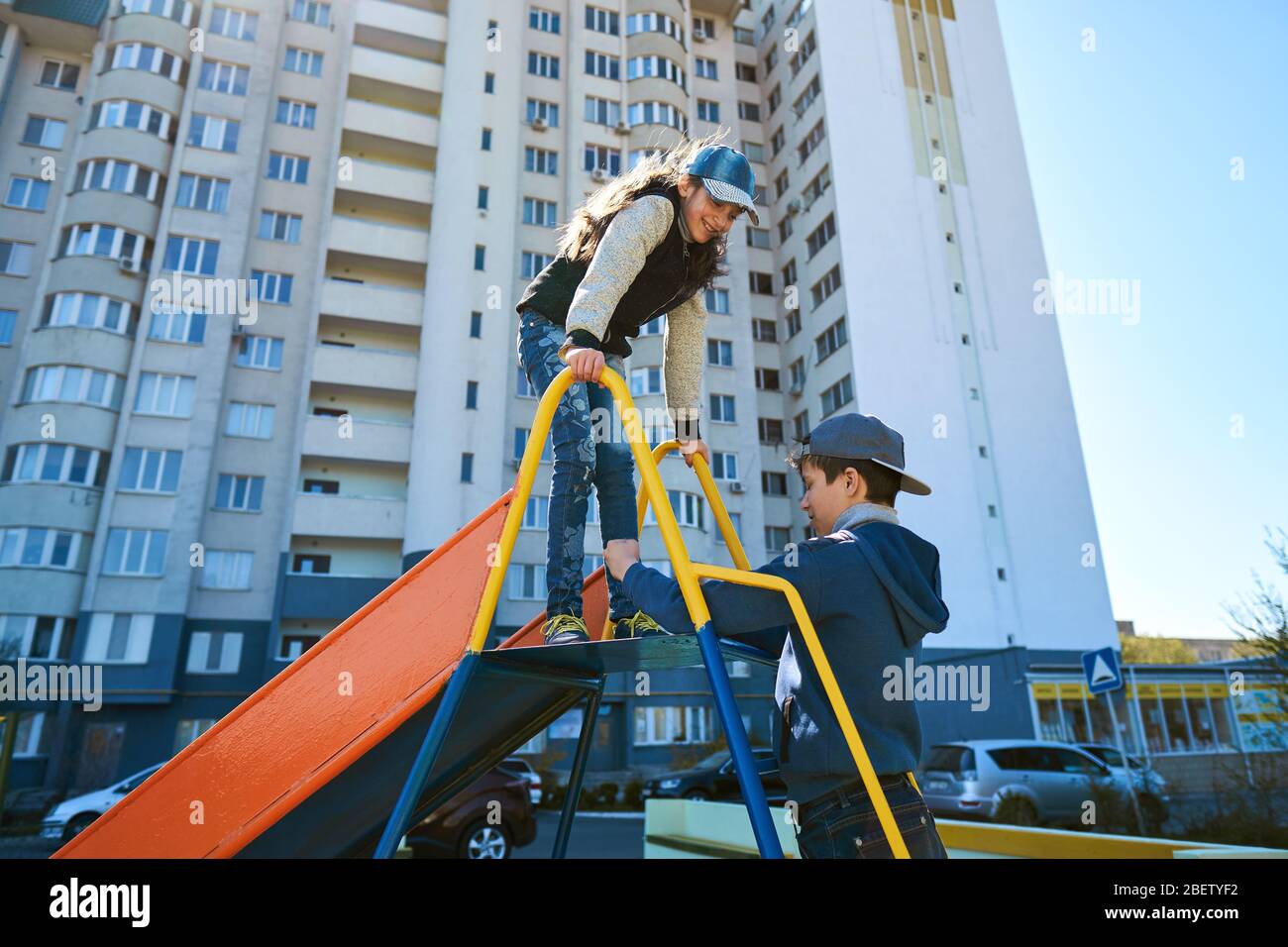 Children play on the playground next to a condominium. Swing, slide ...