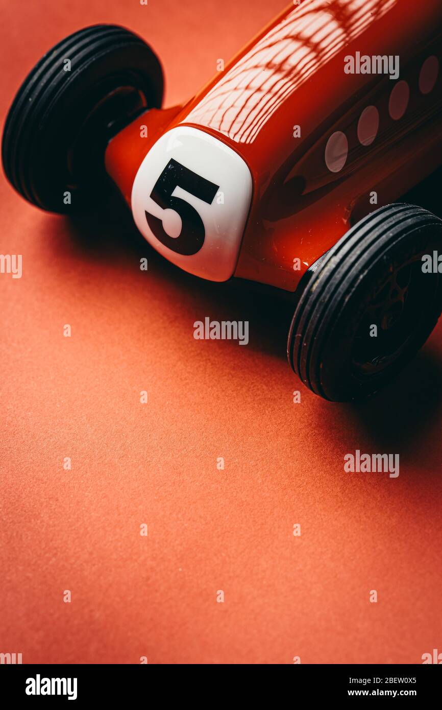 Red toy vintage car with number five on a plate close up still on a red ...
