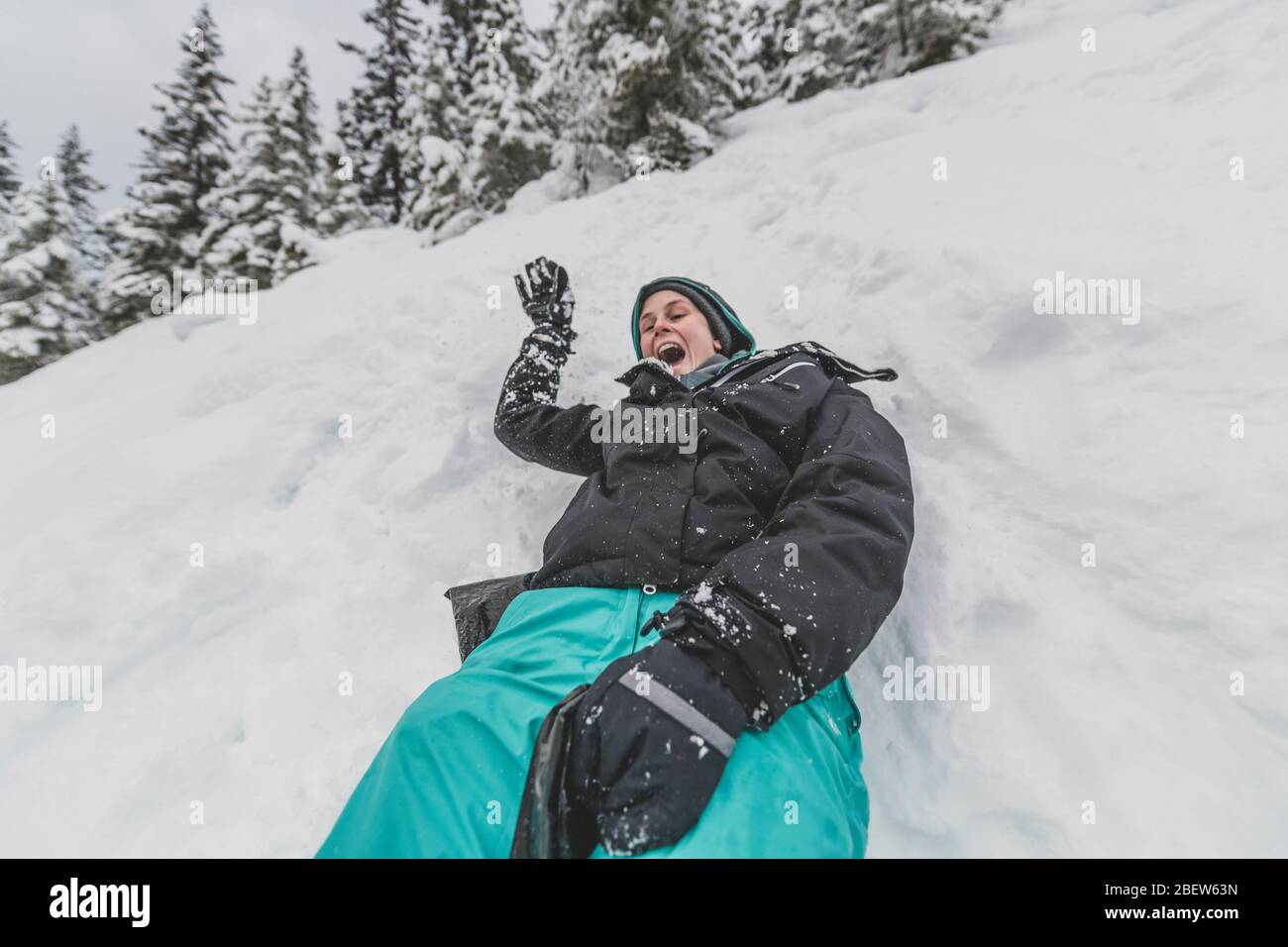 Young woman with hat sliding fast in the snow downhill funny face Stock ...