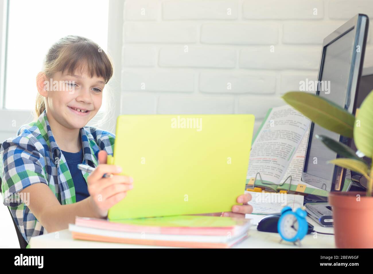 A ten year old girl happily looks at the screen of a tablet computer ...