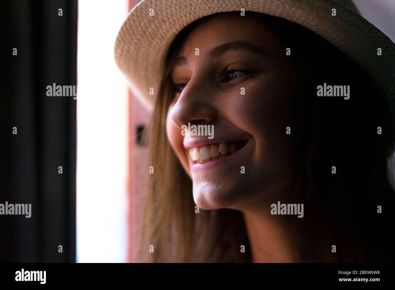 Woman in hat looking out the window Stock Photo - Alamy