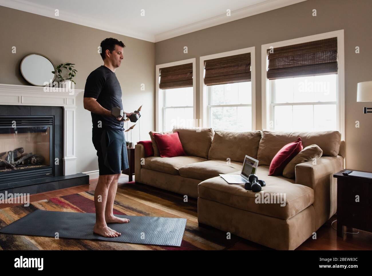 Man working out with weights at home using online exercise program ...