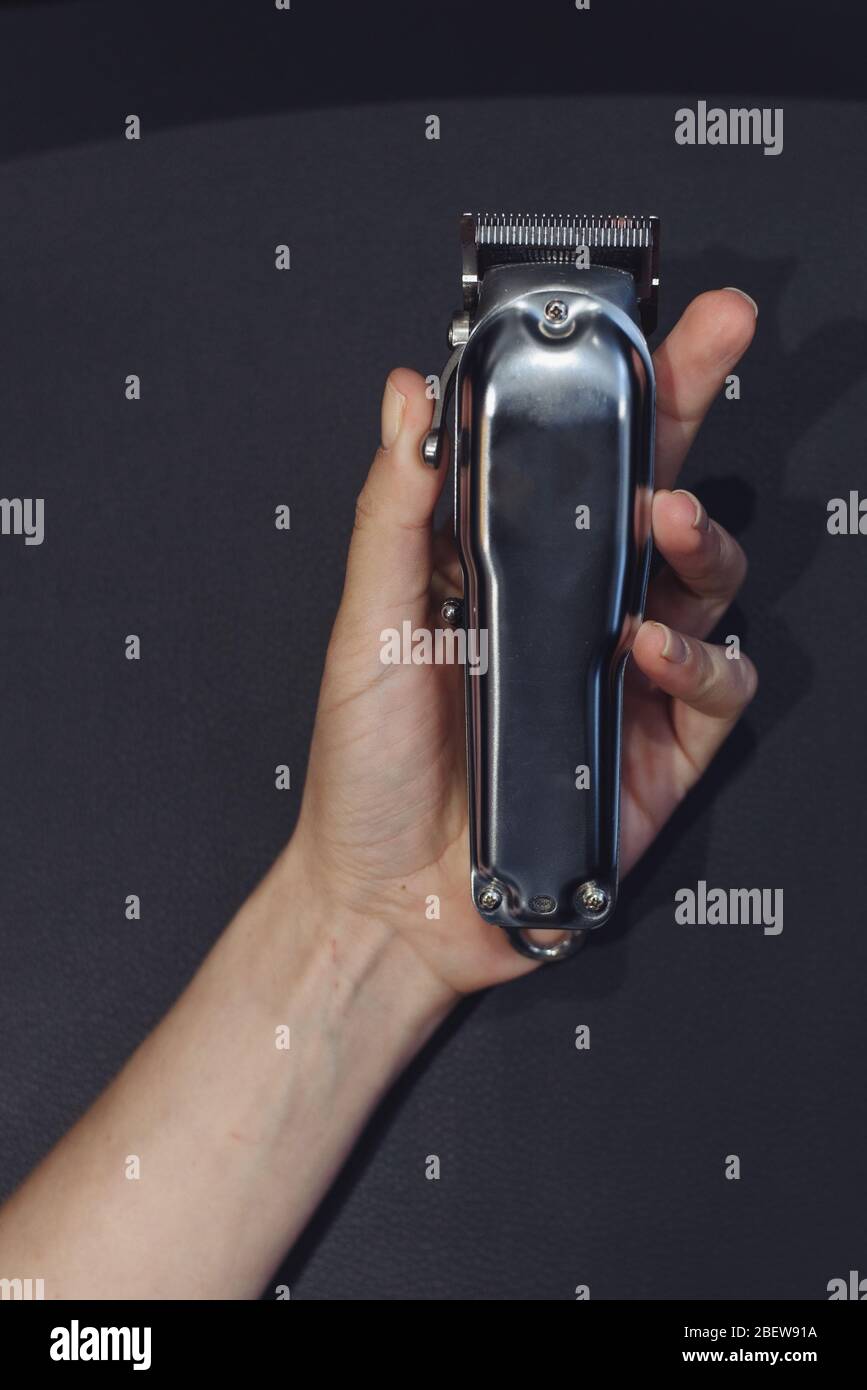 An electric shaver is on black background. Hand is holding razor for ...