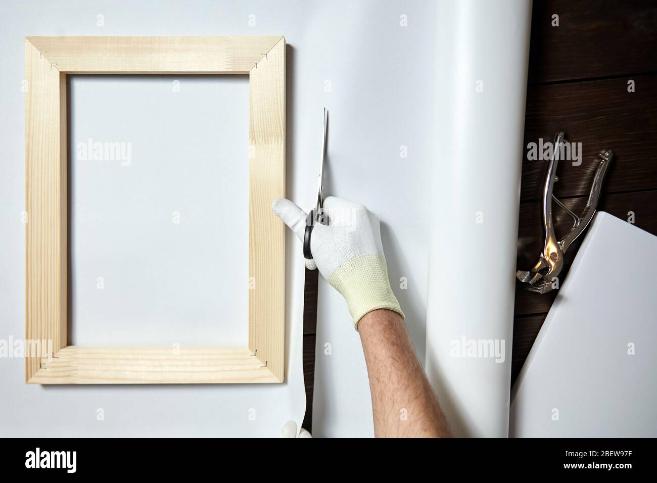 Canvas stretching process. Scissors cutting fabric. Wooden stretcher ...