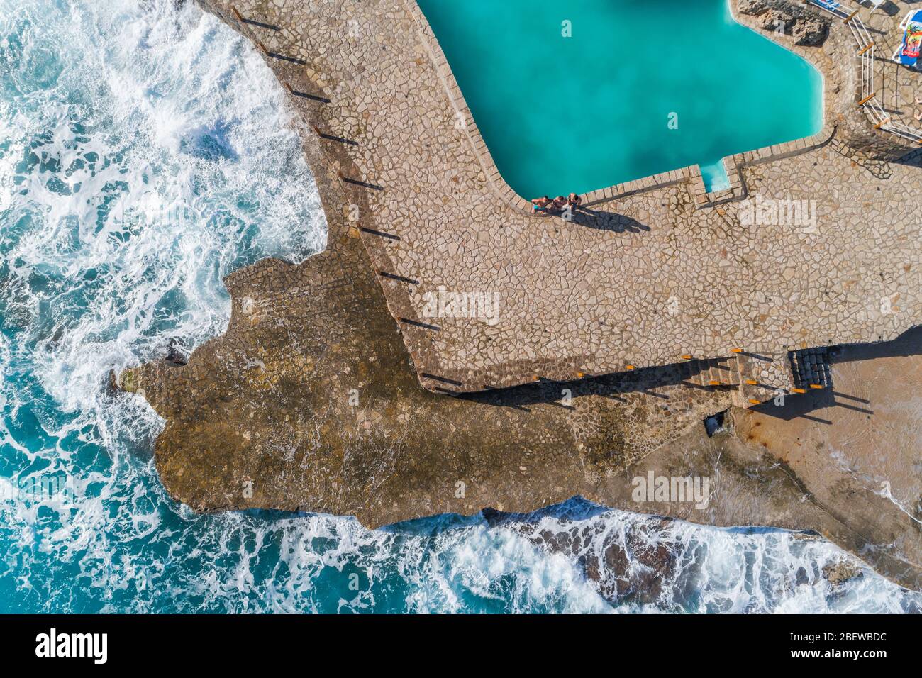 Aerial view of Ploce beach with swimming pool and stormy waves on the ...