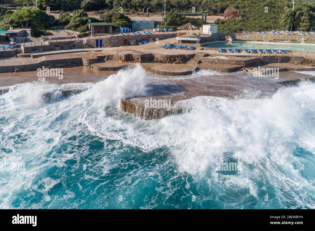 Aerial view of Ploce beach with swimming pool and stormy waves on the ...