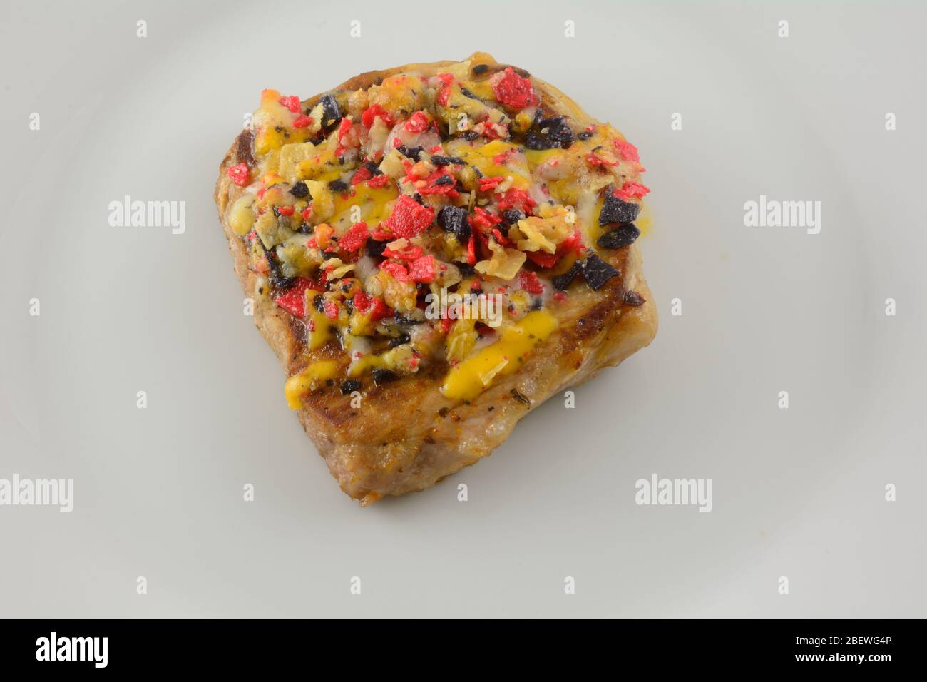 Closeup of baked boneless pork chop with cheese and toppings on whiter ...