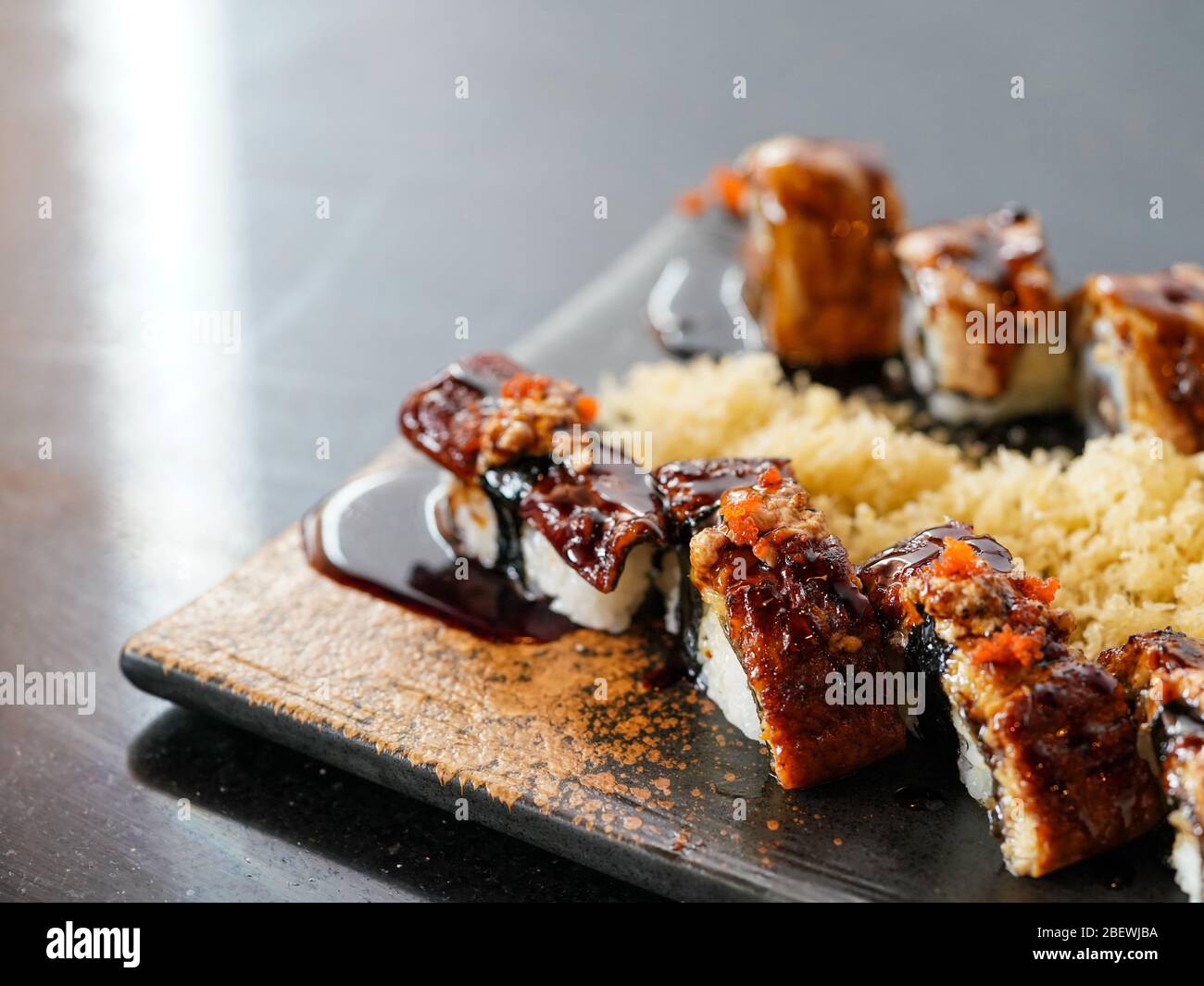 Anago sushi topped with Foie Gras, served with tempura crust on a black ...